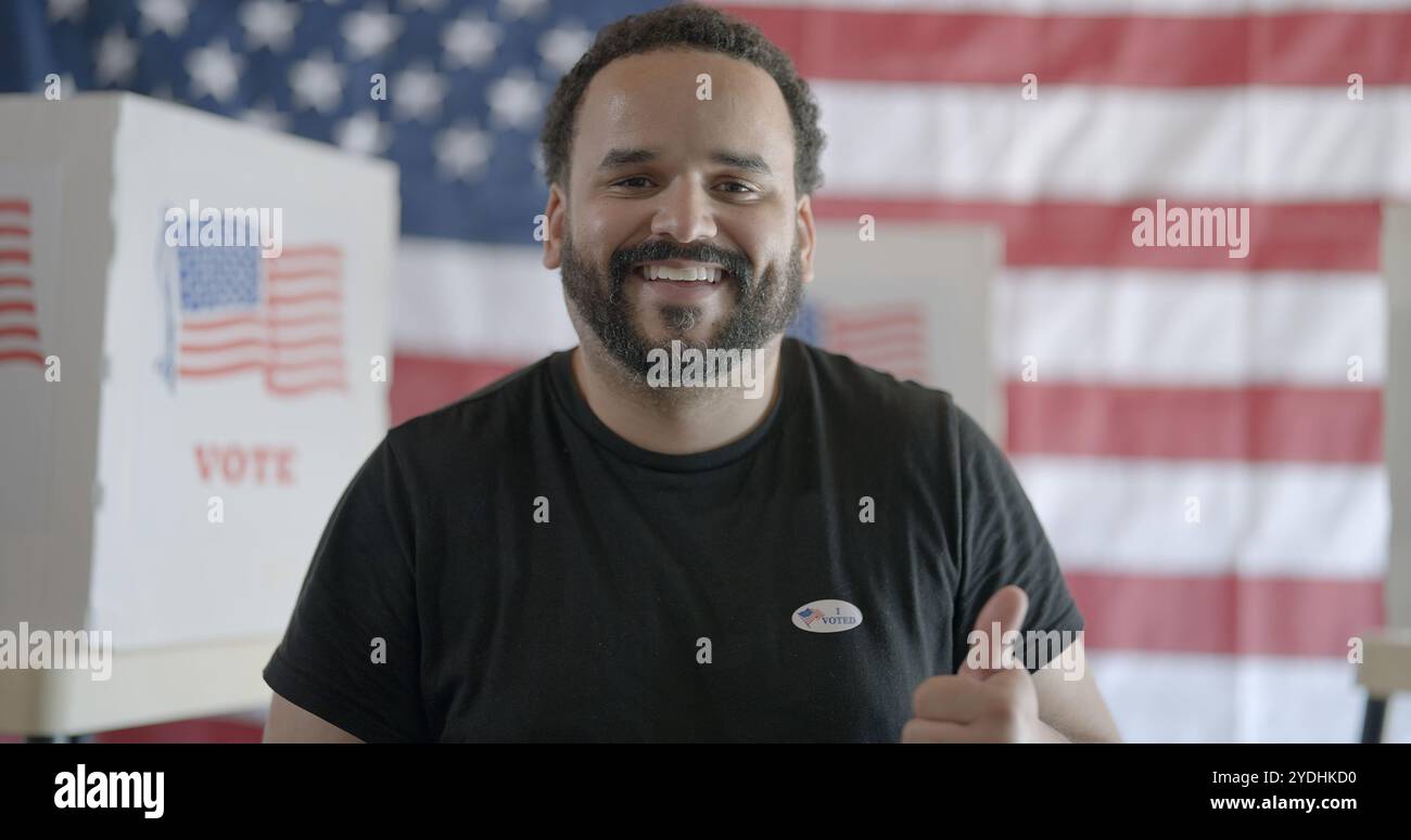 Dark skinned man gives thumbs up to camera while wearing I voted ...