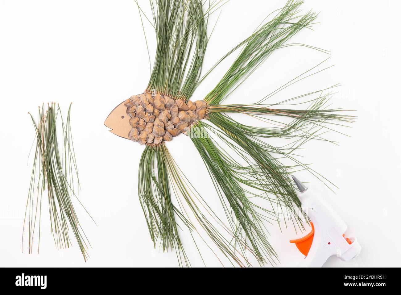 cardboard cut into the shape of a fish, with small pine cone scales ...