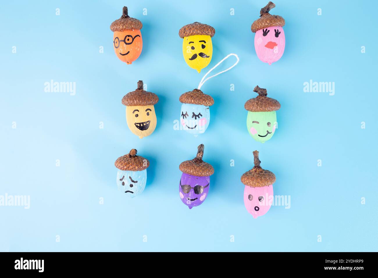 Painted acorns with faces, various colors, 3x3 grid, light blue ...