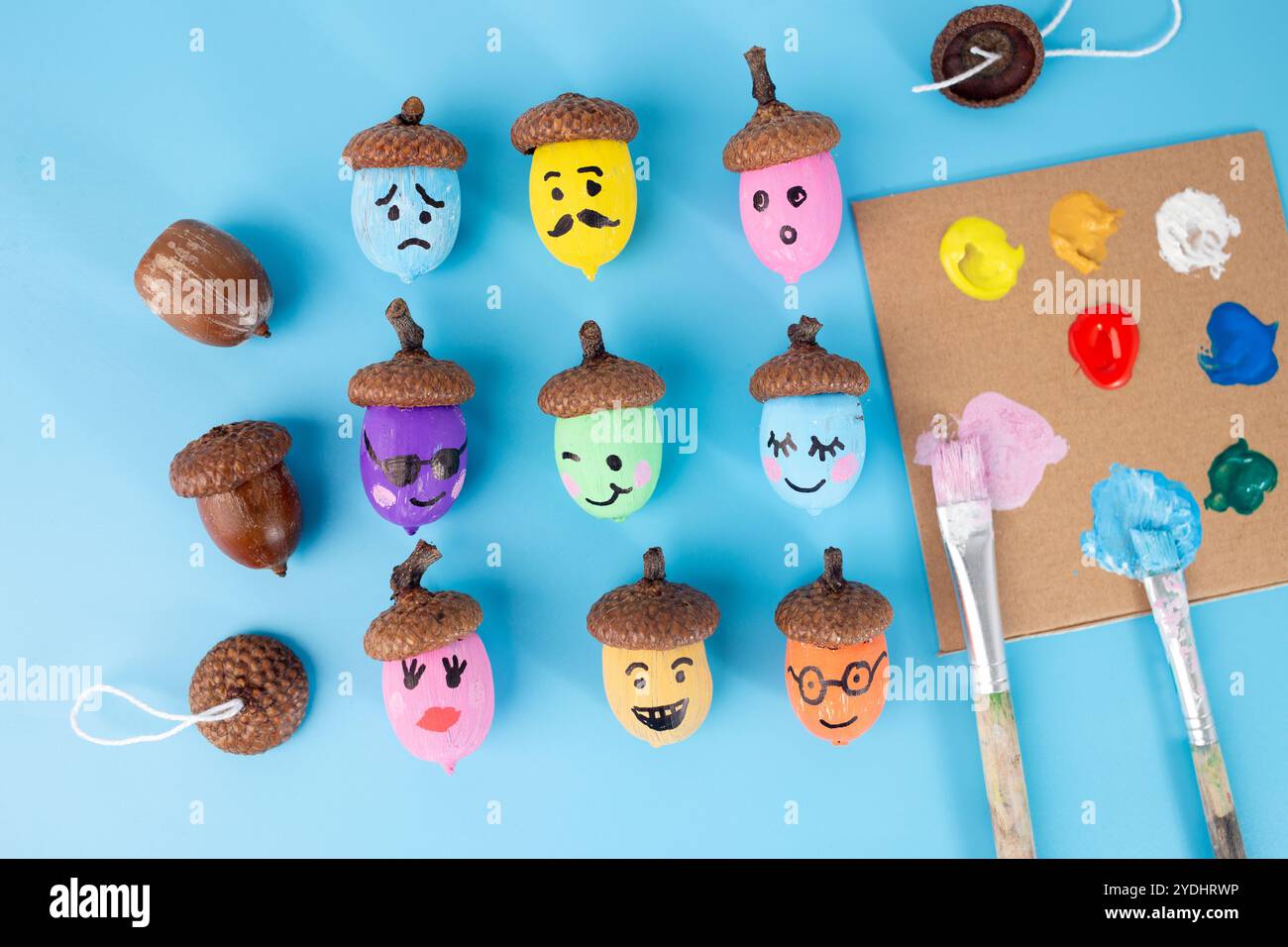 Emoji faces acorns in colorful paint on blue background. Flat lay ...