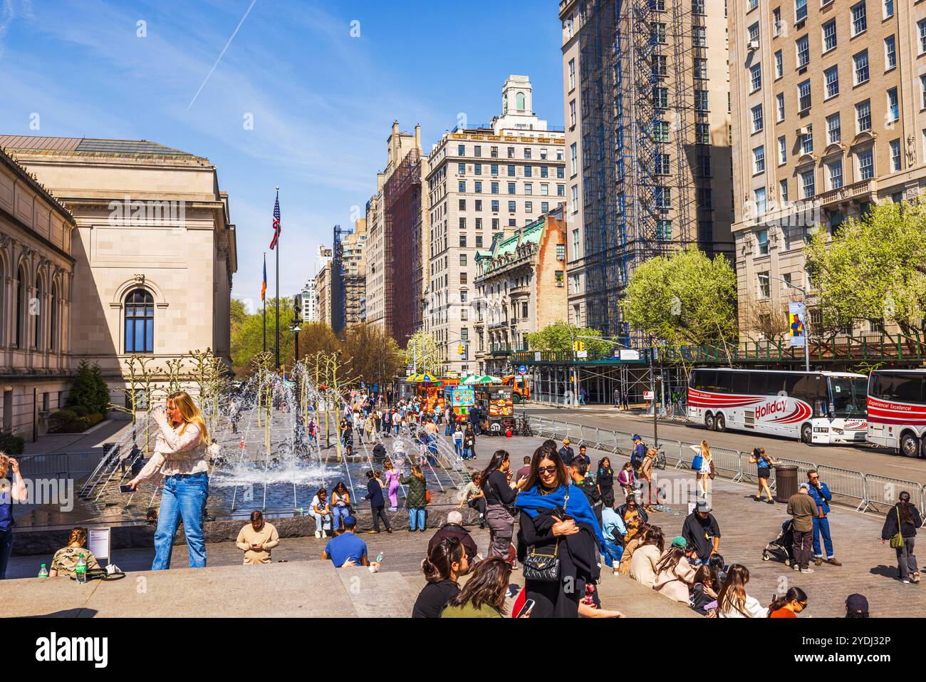 Busy plaza with fountain, tourists, and food vendors under clear skies ...