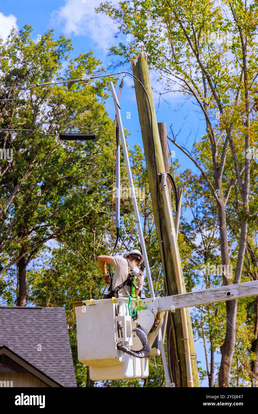 Lineman operates from raised lift to inspect maintain power transformer ...