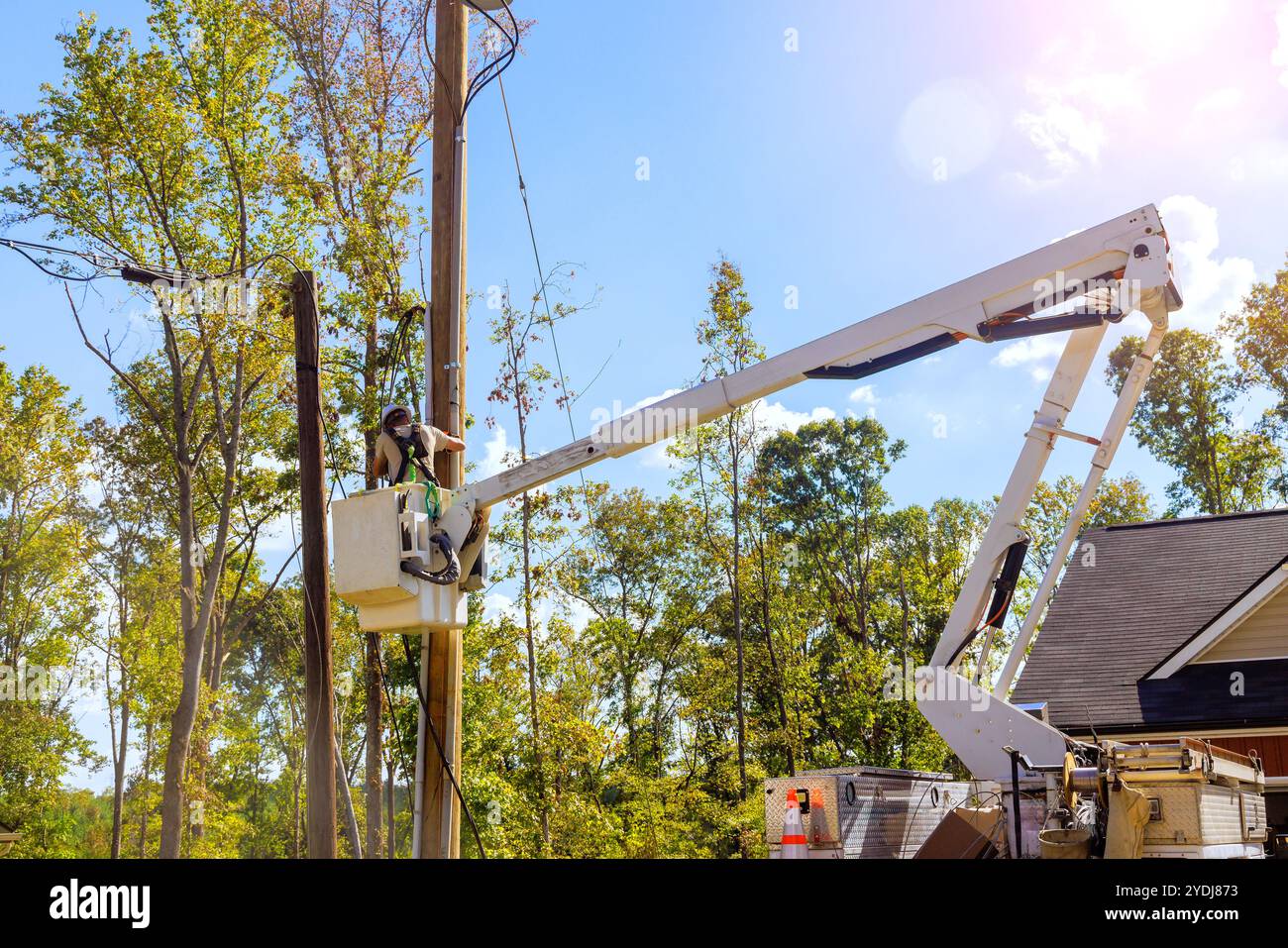 Lineman performing overhead electrical maintenance using bucket lift ...