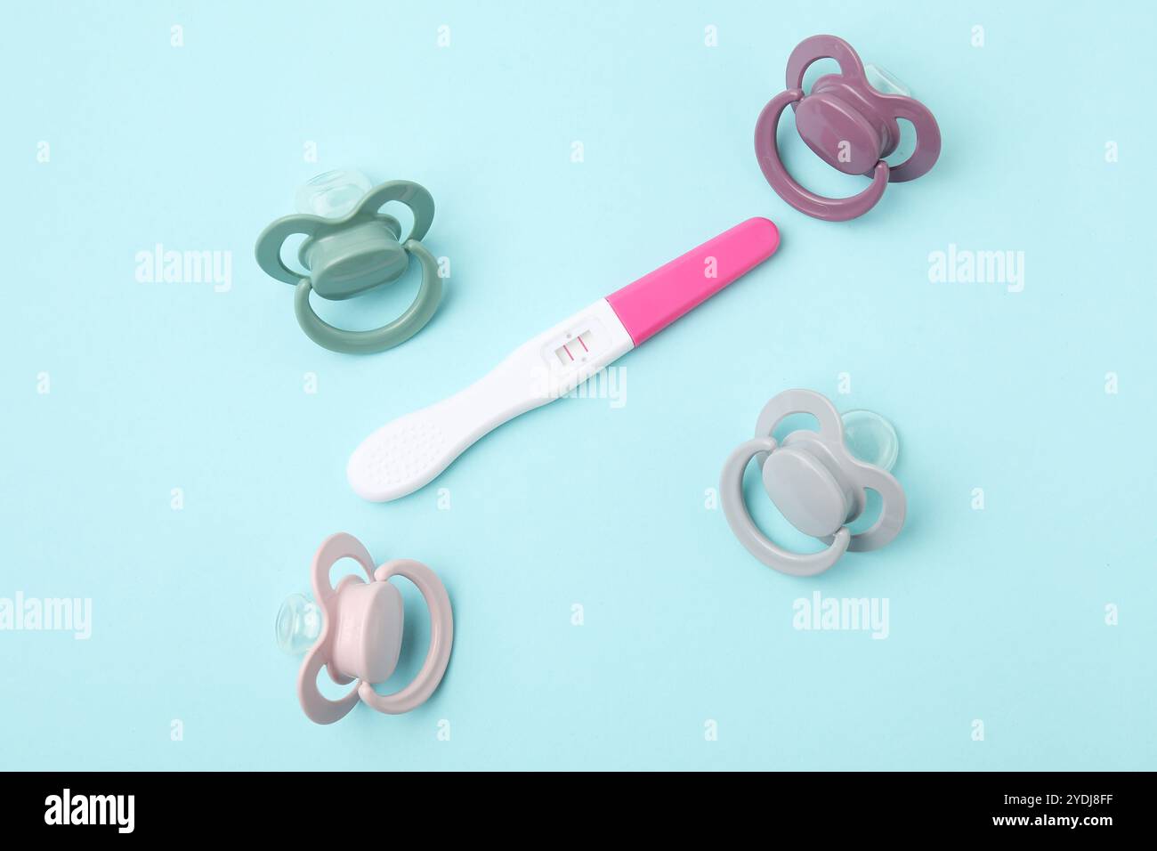 Pregnancy test and pacifiers on light blue background Stock Photo - Alamy