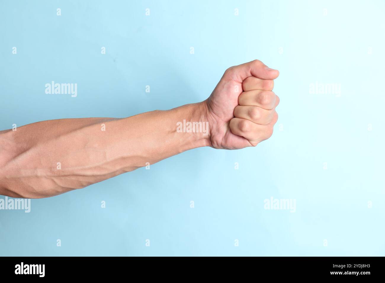 Man with bulging veins on his arm against light blue background ...