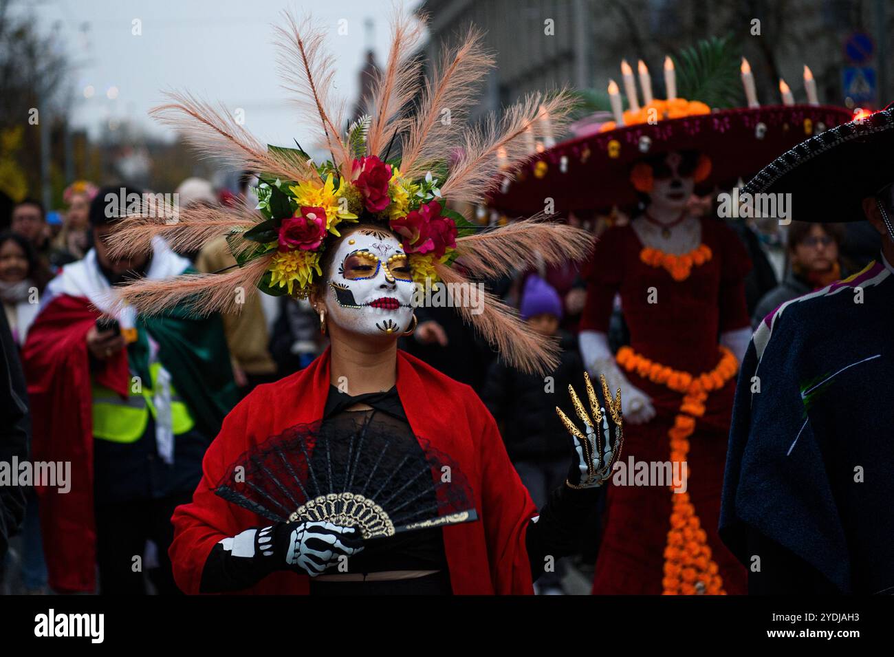 People in traditional Mexican costumes and skull makeup take part in a ...