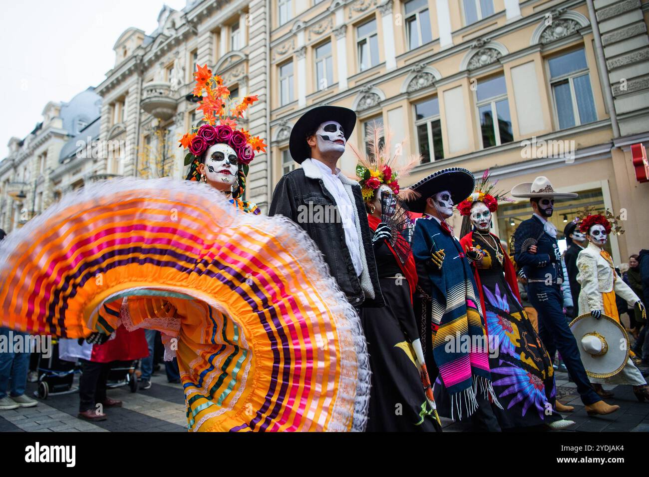 People in traditional Mexican costumes and skull makeup take part in a ...
