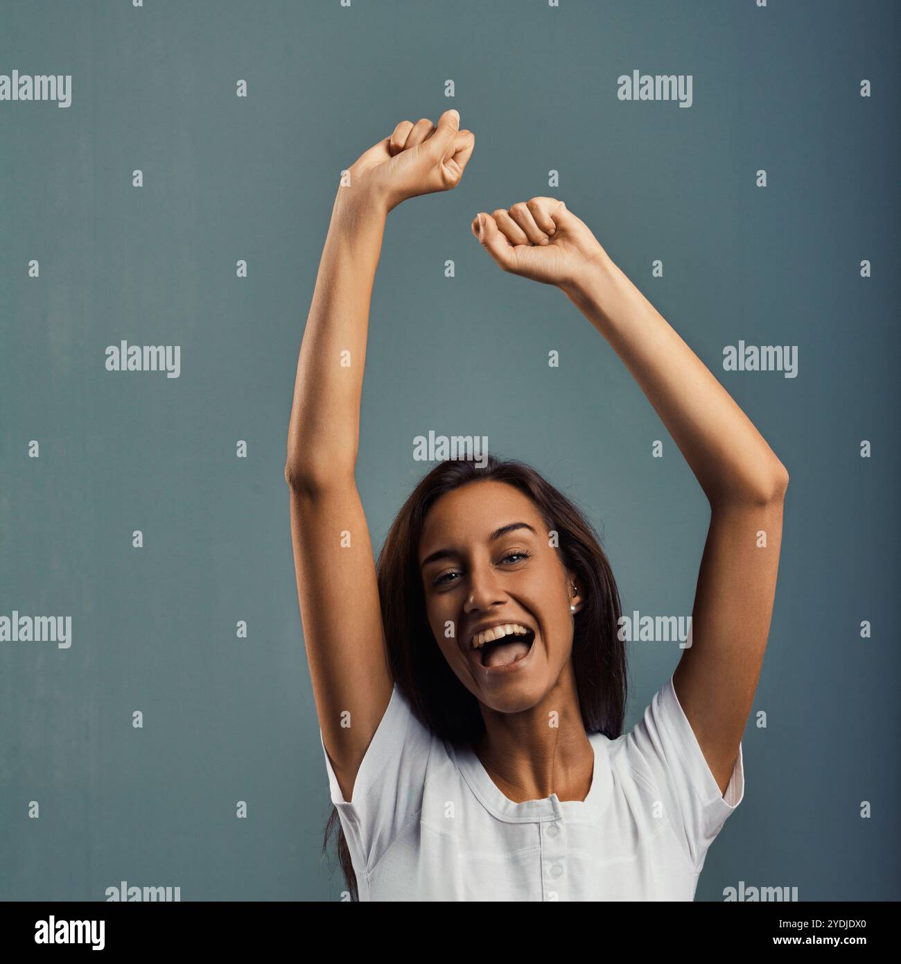 Studio portrait of a cheerful young latin woman raising her arms and ...