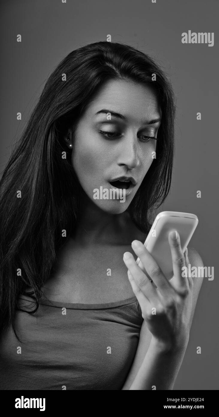 Black and white portrait of a surprised young woman reading shocking ...
