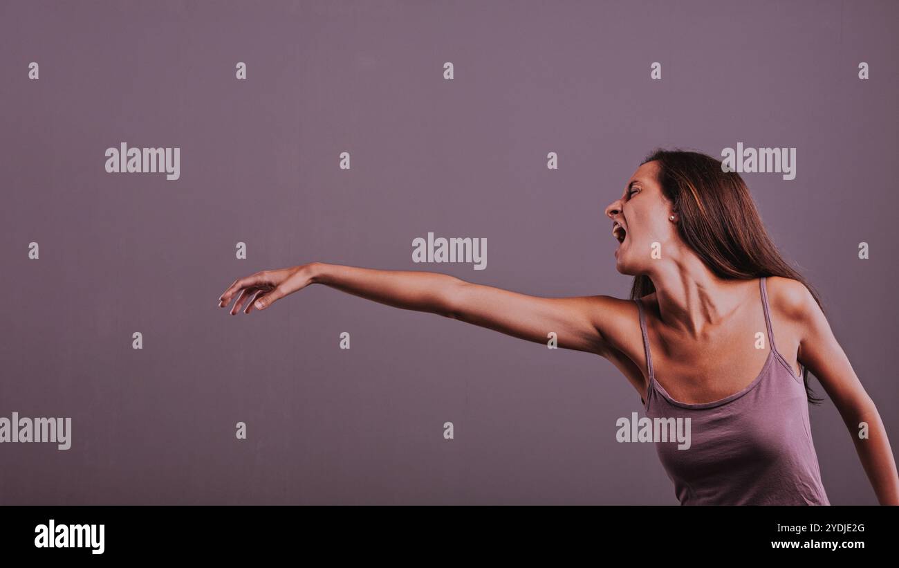 Expressing intense emotion, a young woman extends her arm and shouts ...