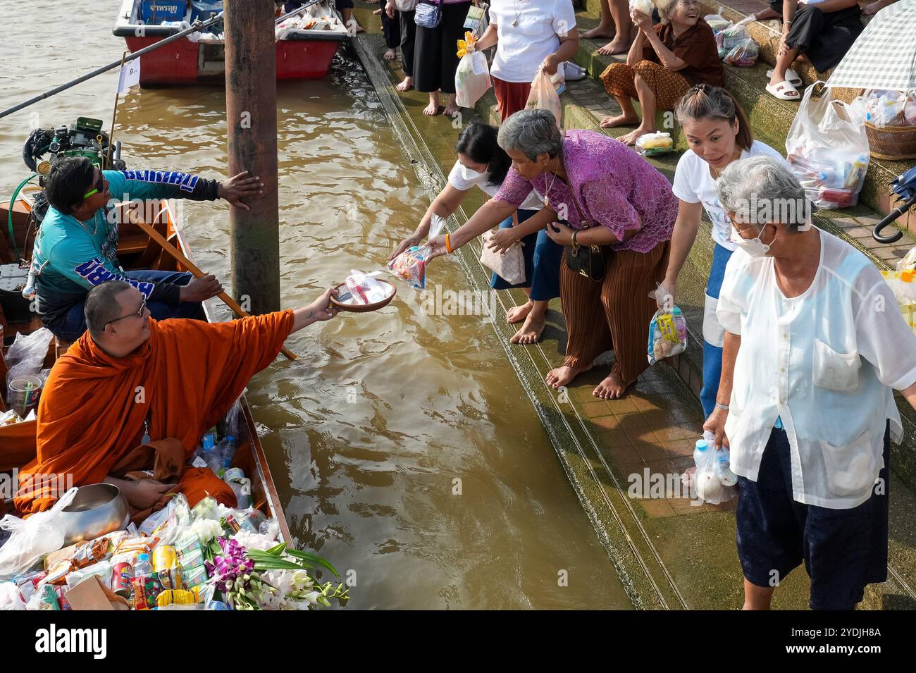 A monk who is sitting in a rowboat is seen holding out his hand to ...