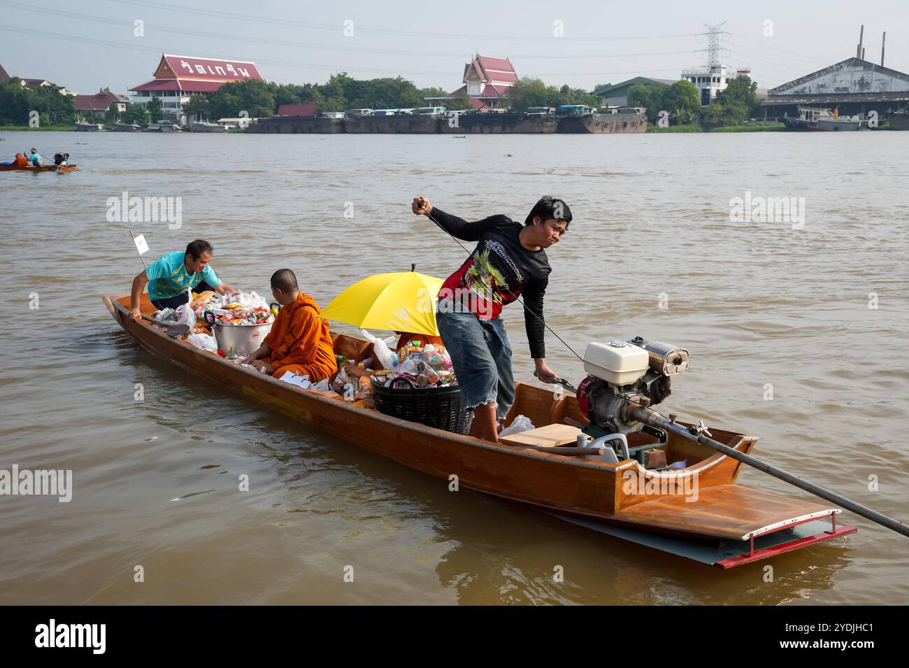 A row boat driver is seen starting the boat's engine while a monk sits ...
