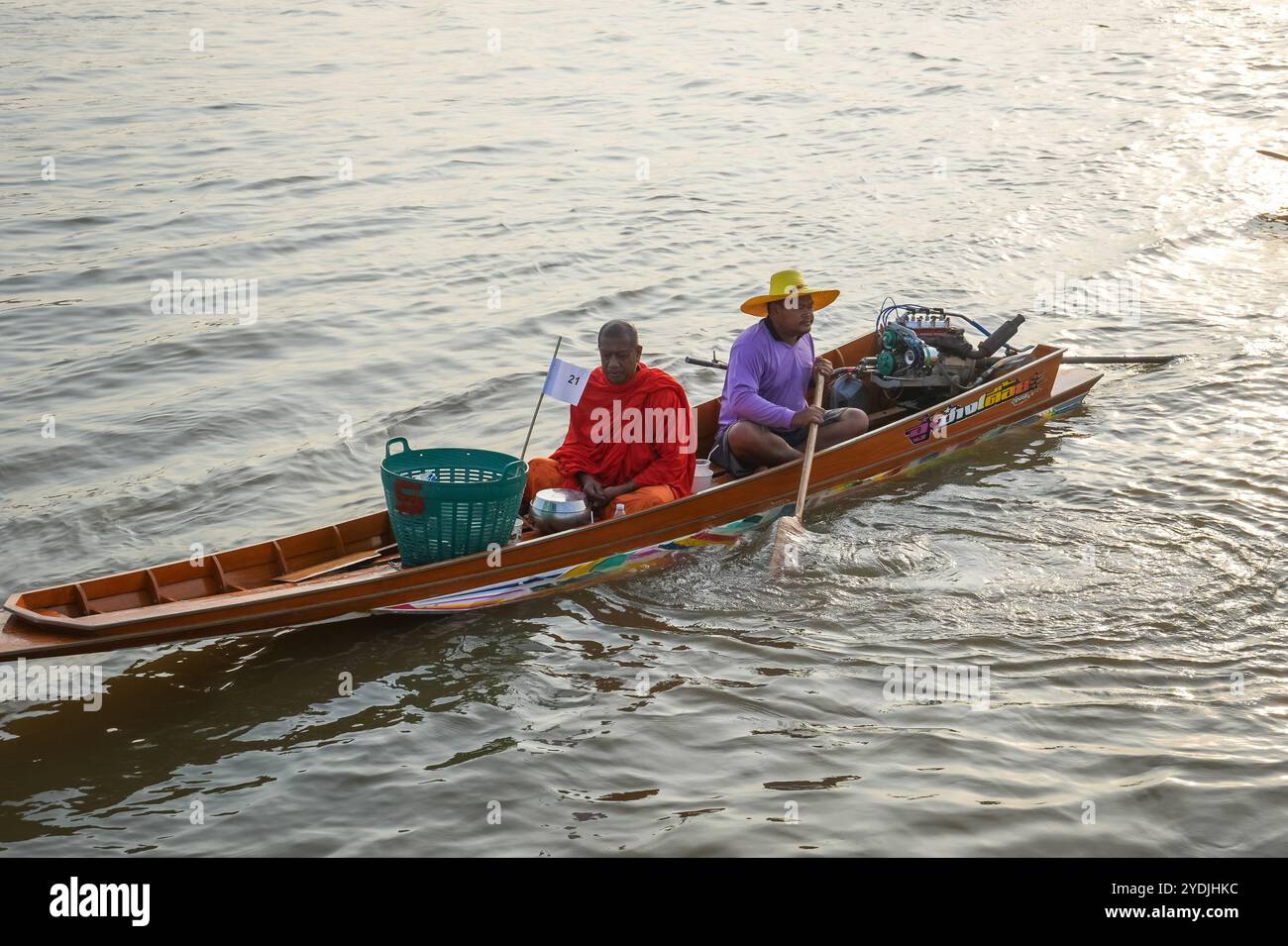 A close view of a monk with his driver on a rowboat at sunrise, at ...