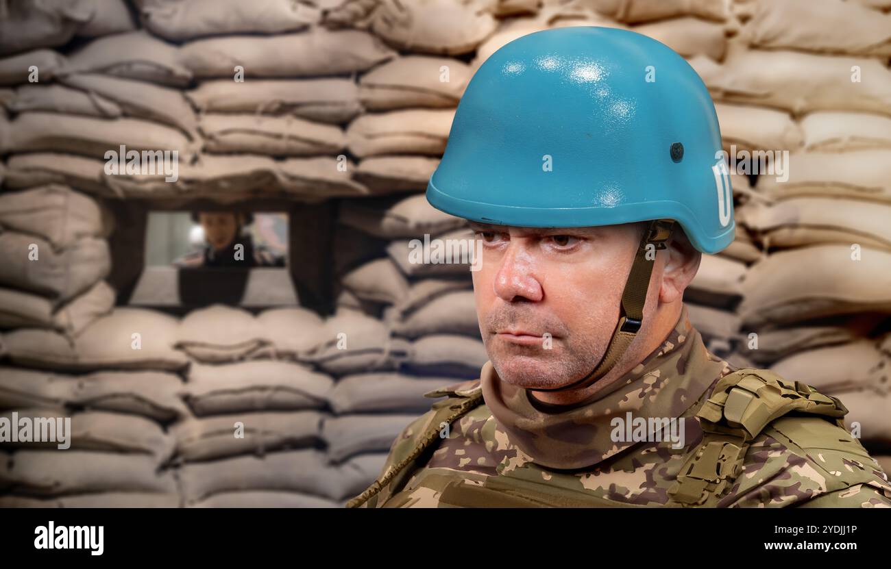 A soldier with a blue helmet stands in front of a sandbag wall Stock ...