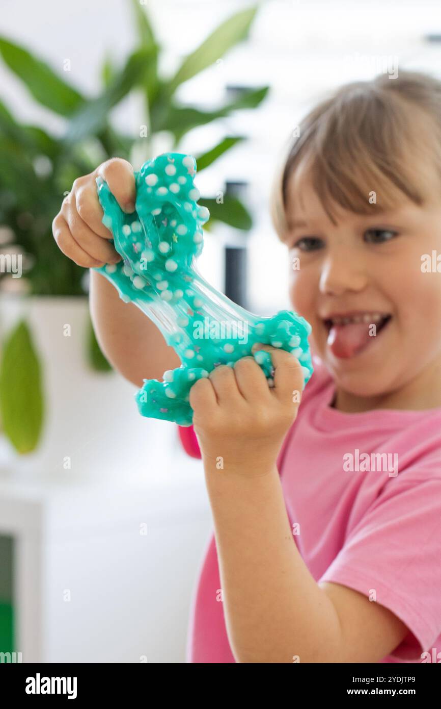 A cute girl playing with bright, blue slime, enjoying a fun and ...