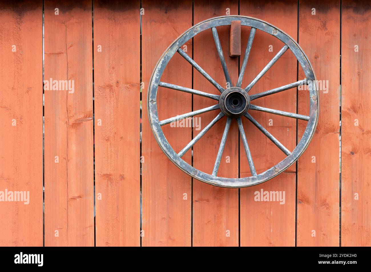 Old wagon wheel on rustic red wood background Stock Photo - Alamy