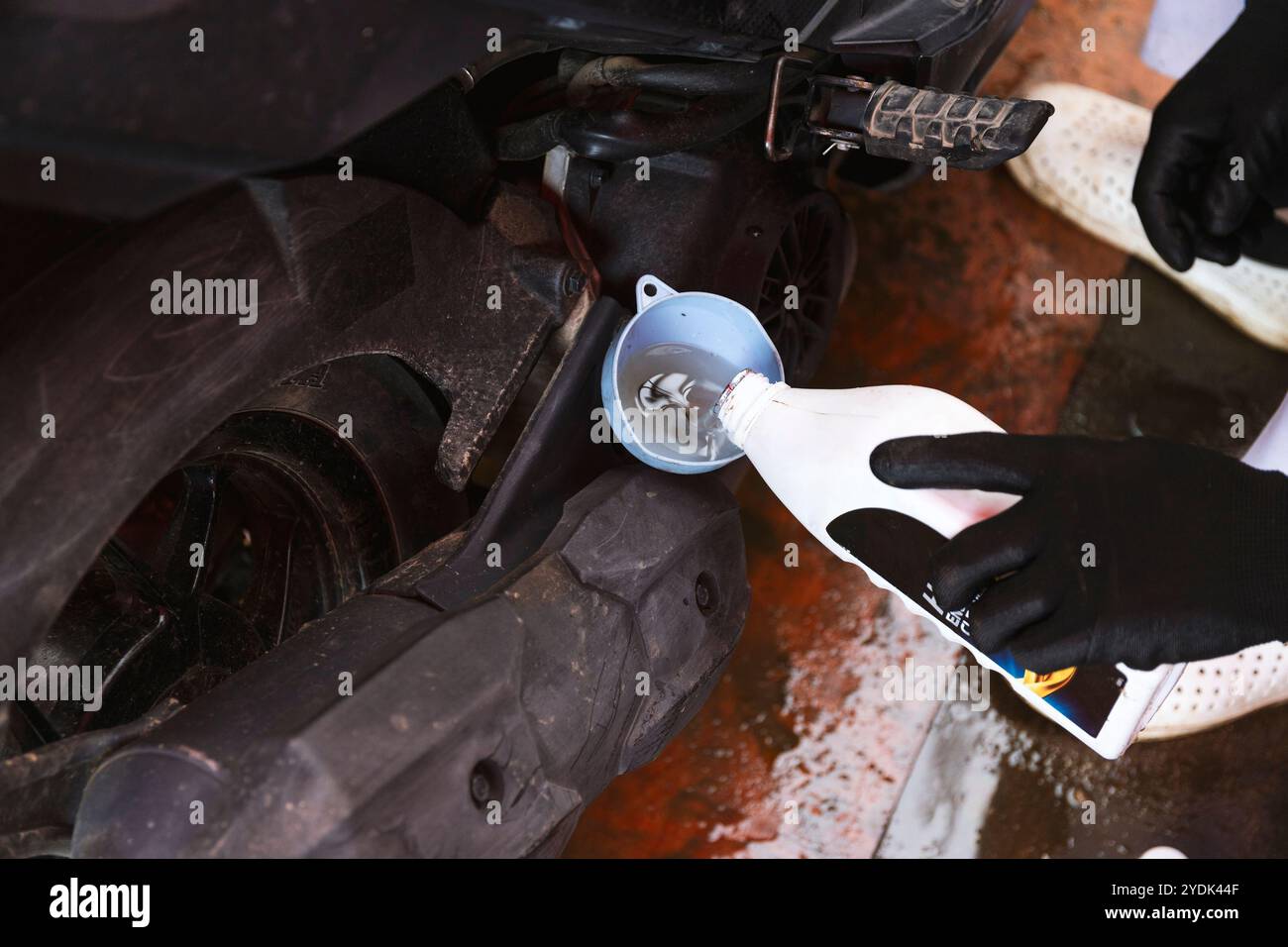 Closeup of a mechanic pouring motor oil into a motorcycle engine ...