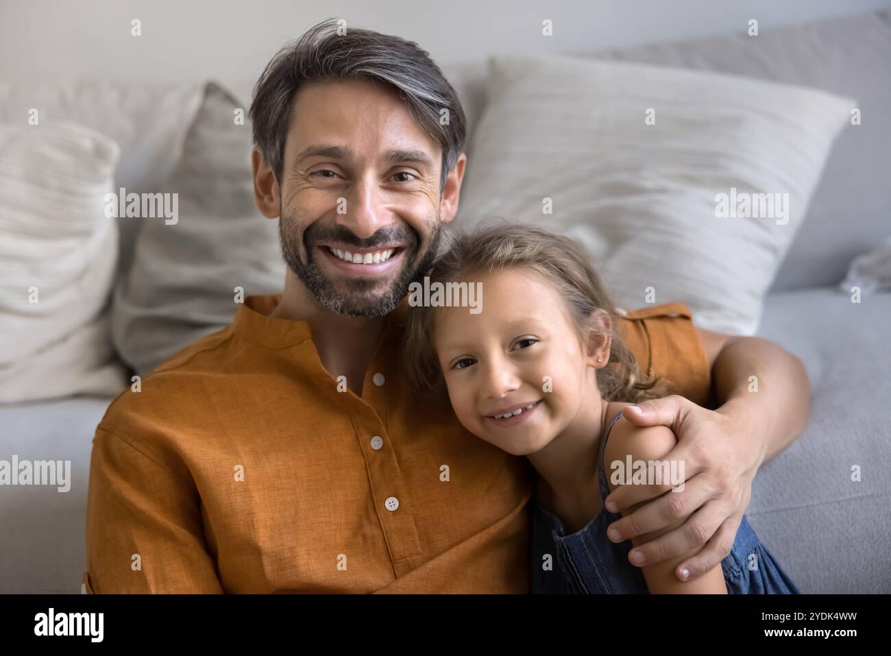 Happy handsome Hispanic dad hugging daughter kid looking at camera ...