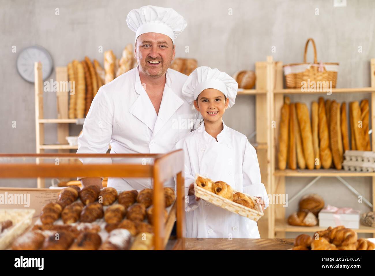 Father baker poses with his young daughter who helps sell fresh bread ...