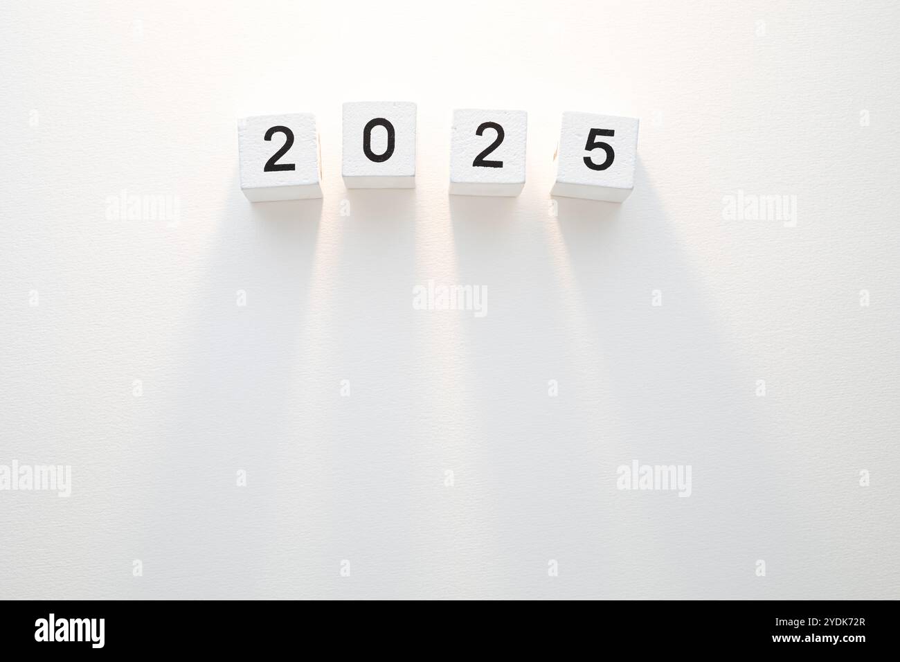 Year 2025 displayed on white cubes casting shadows against a simple ...