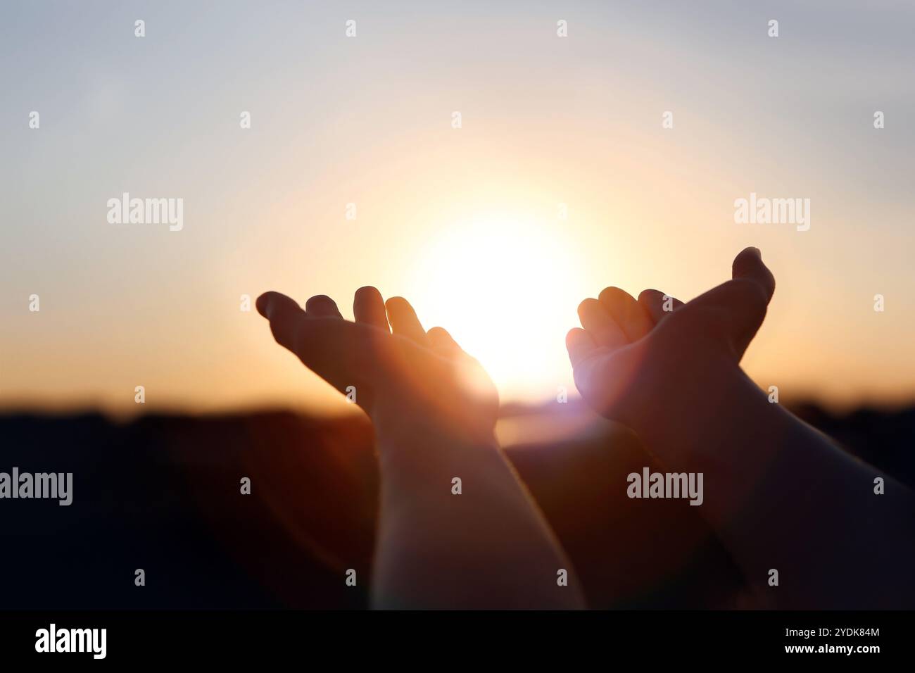 Sunlight shining through hands stretched out toward the sunrise Stock ...