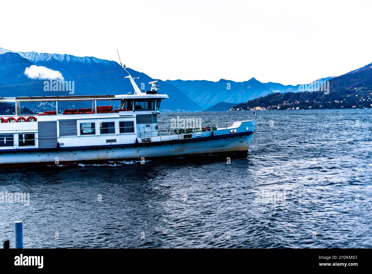 bow of old ferry sailing on lake with white colors and mountains in ...