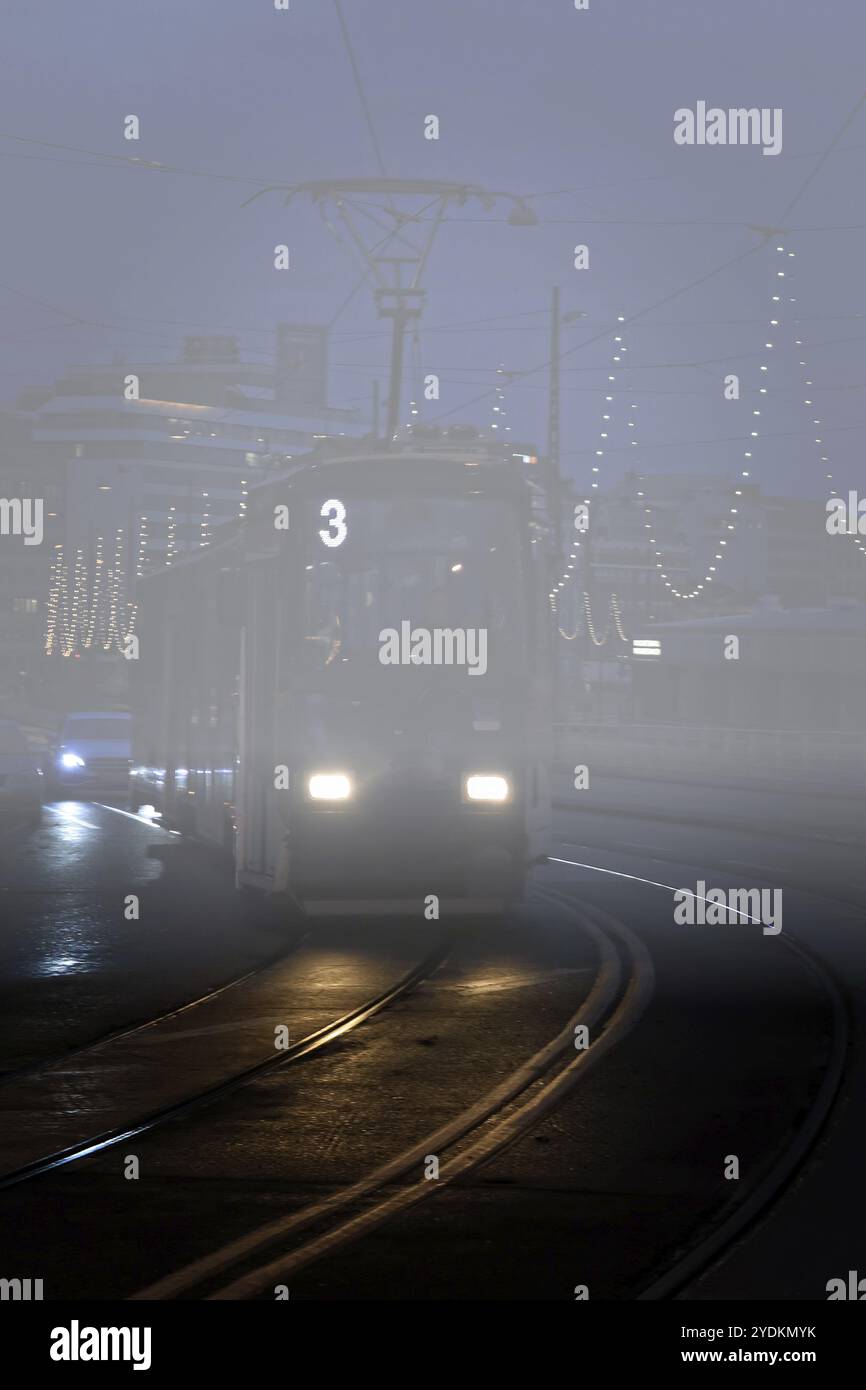 Tram arriving to tram stop on a dark, foggy November morning. Helsinki ...