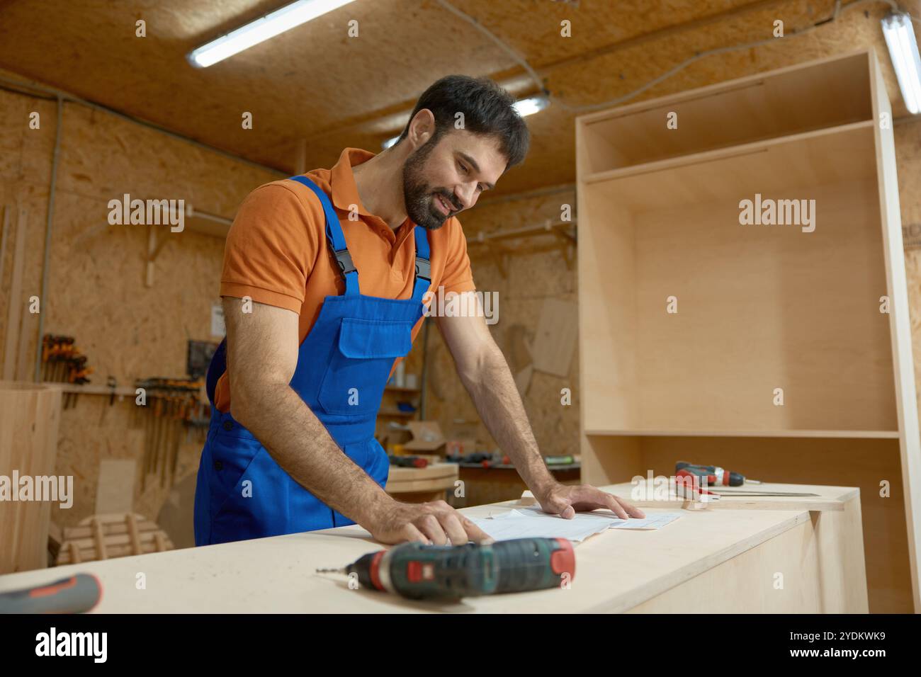 Handyman measuring with ruler during furniture production process at ...