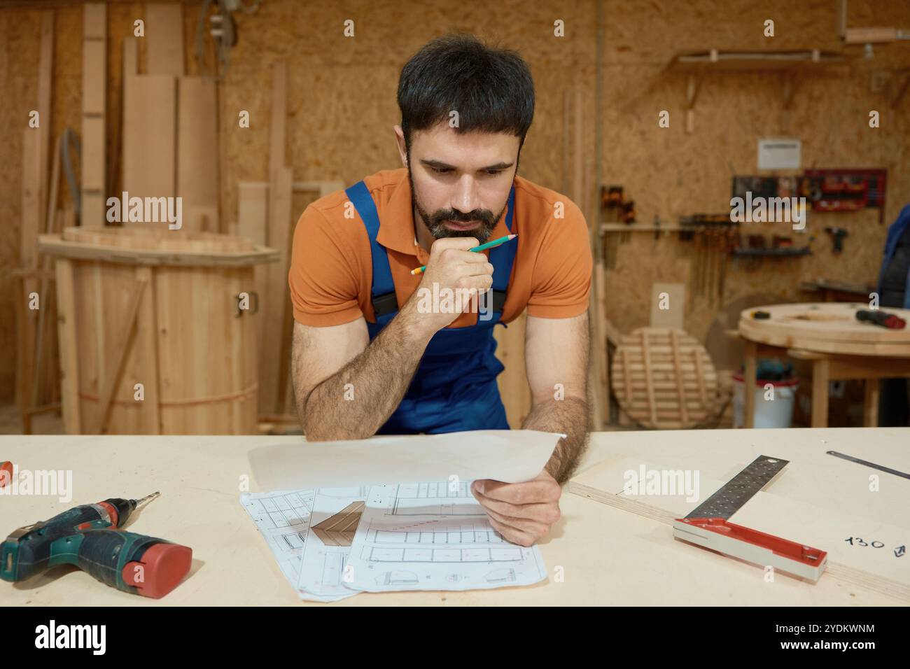 Carpenter reading blueprints and thinking during woodworking process ...