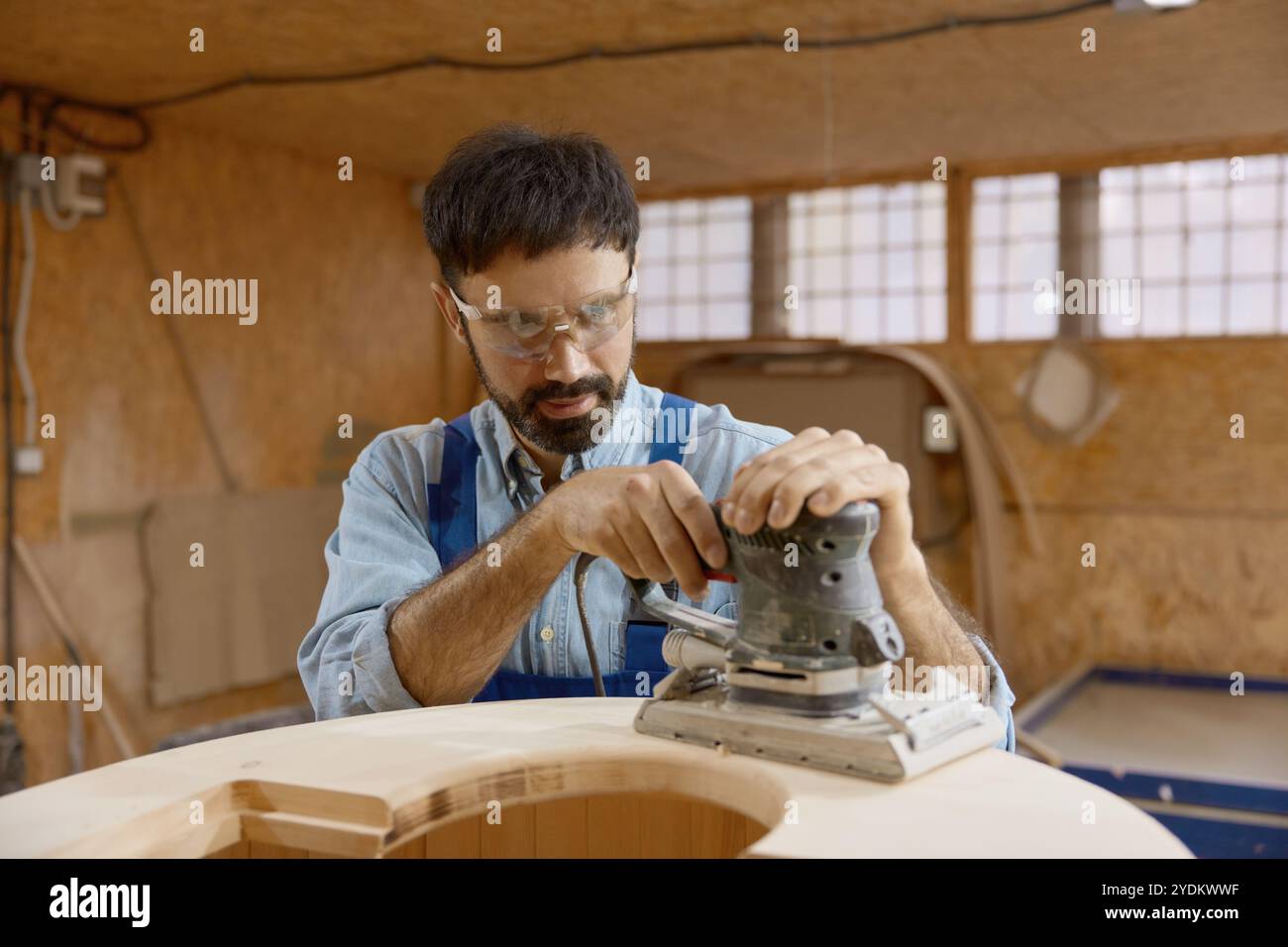 Carpentry studio worker using grinding machine for finishing wood ...