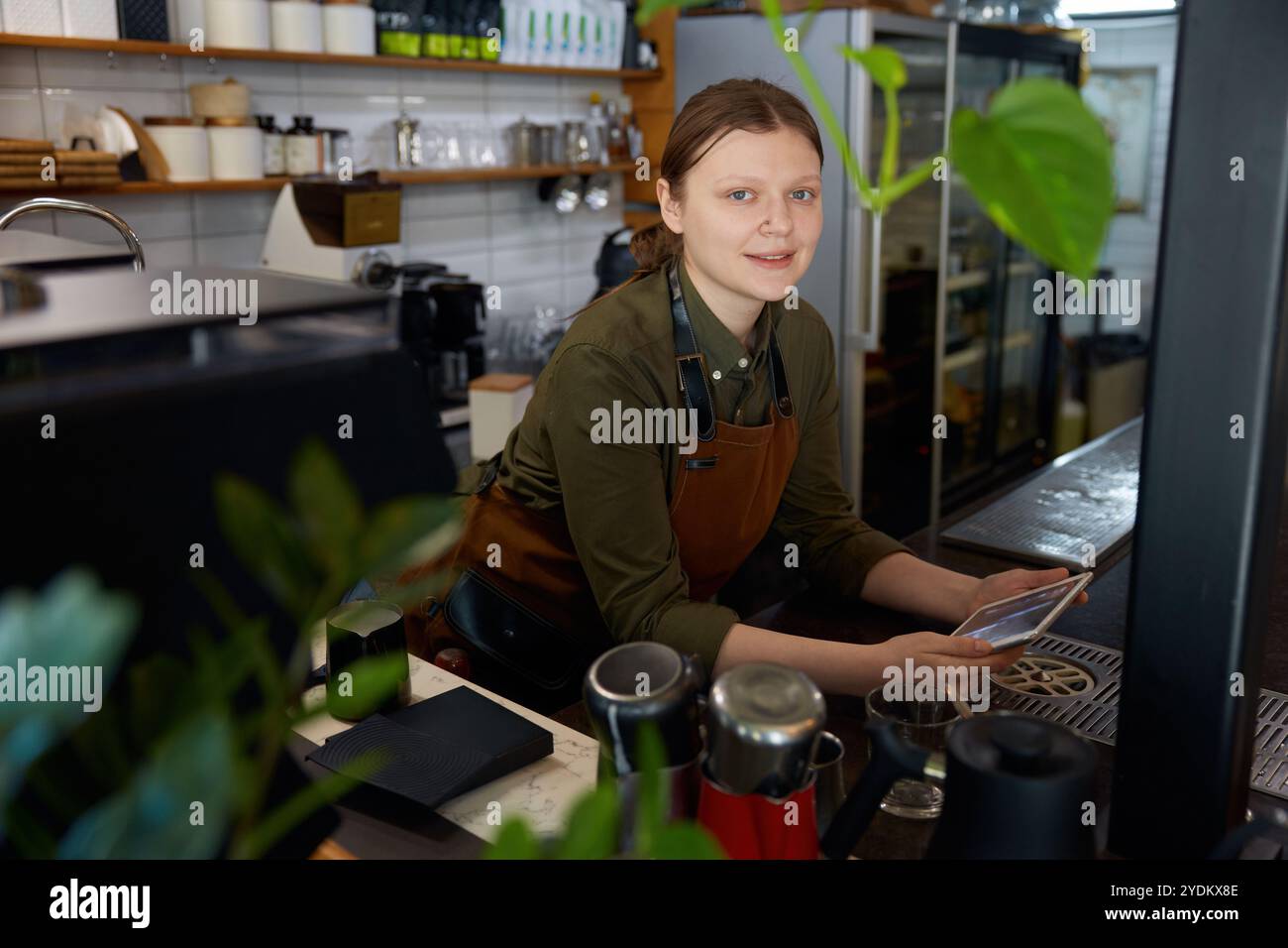 Young woman barista with mobile tablet at coffee shop counter desk ...