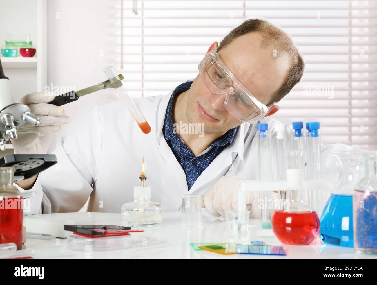 Scientist in goggles and a white coat is conducting experiments in a ...