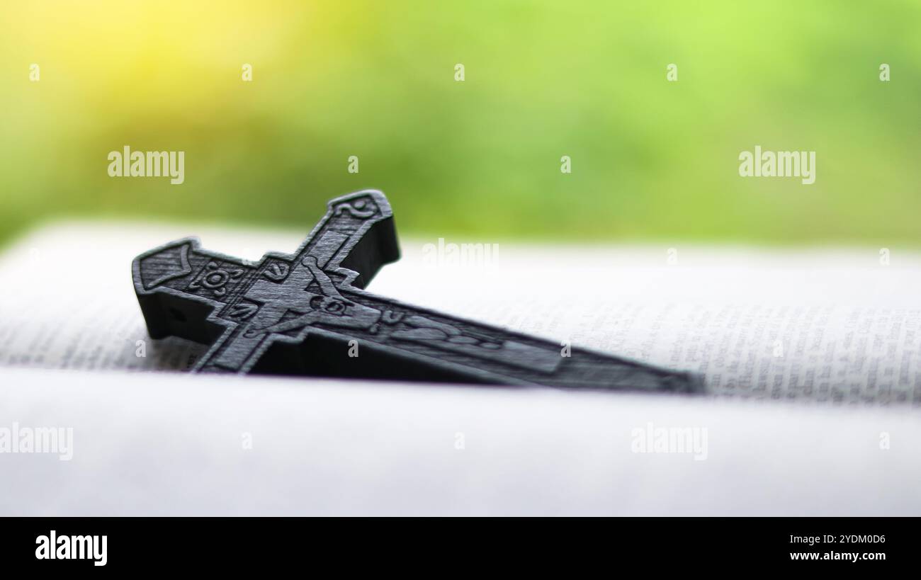 Dark brown wooden cross on an old open book symbolizing the spread of ...