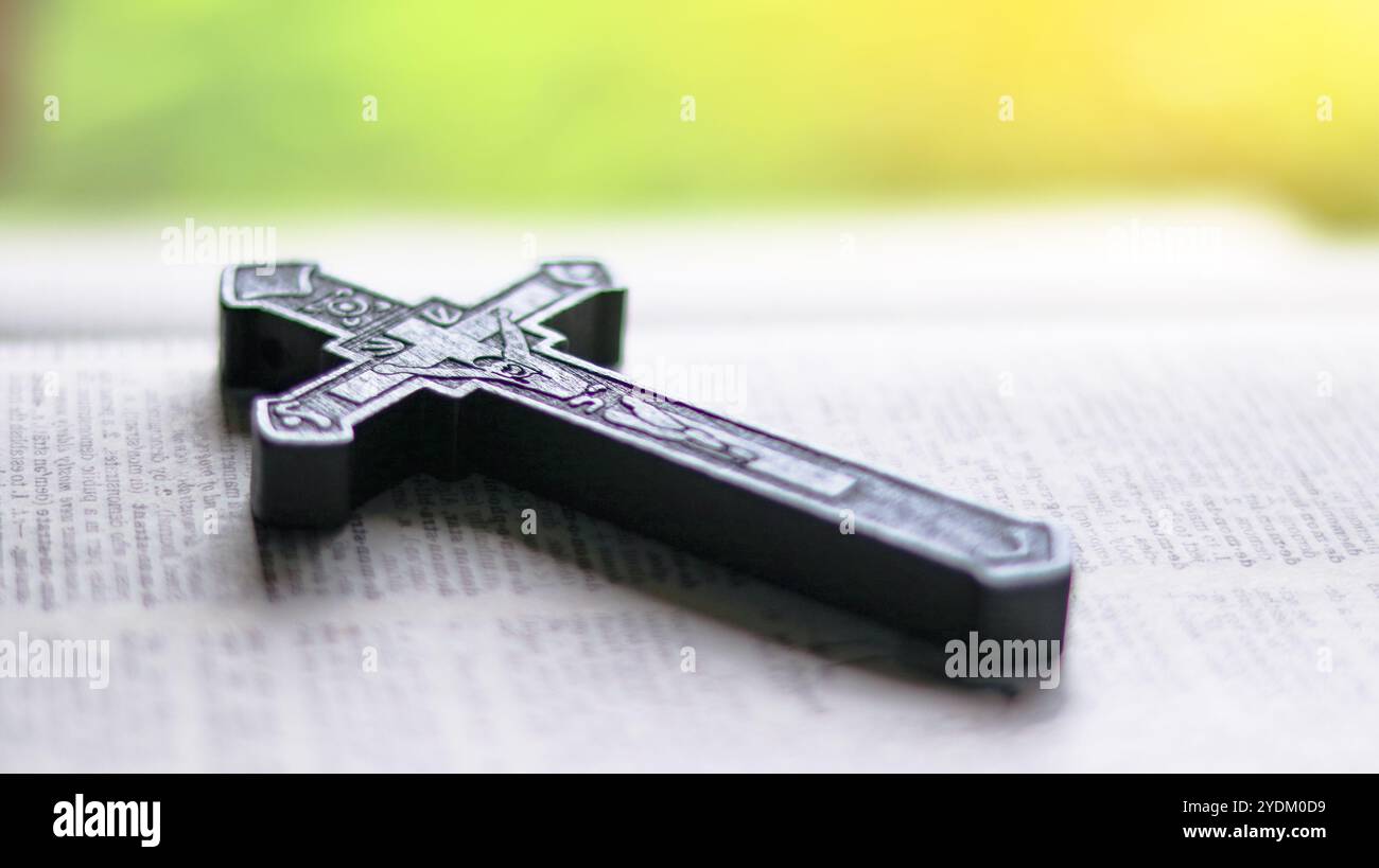 Dark brown wooden cross on an old open book symbolizing the spread of ...