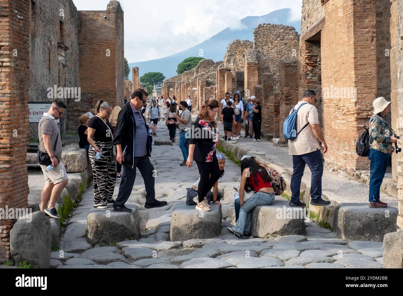 Tourists use stepping stones to cross a cobbled street in the ...