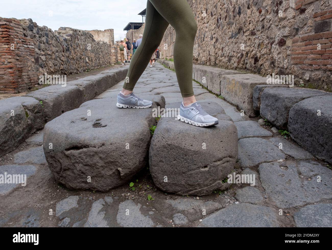 A tourists uses stepping stones to cross a cobbled street in the ...