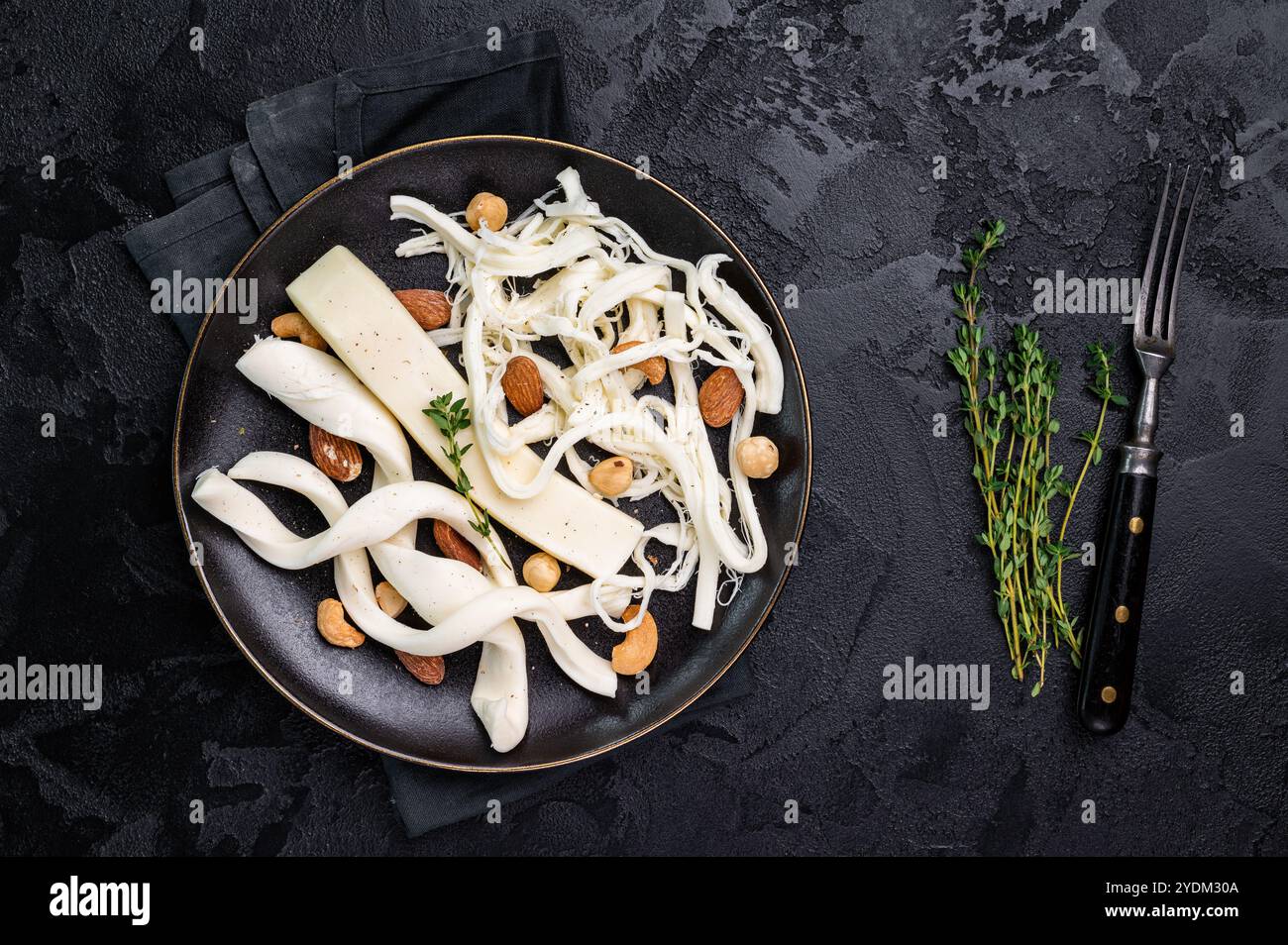Smoked Traditional Chechil white cheese on a plate with nuts, black ...
