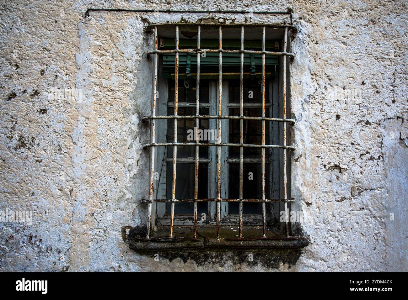 old window with rusty grate wall of an old country house closed by iron ...