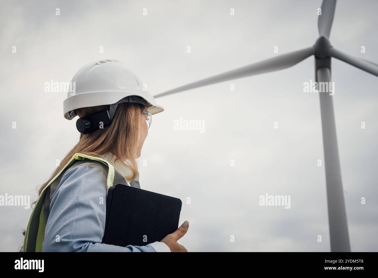 A skilled female engineer is managing wind turbine operations, playing ...