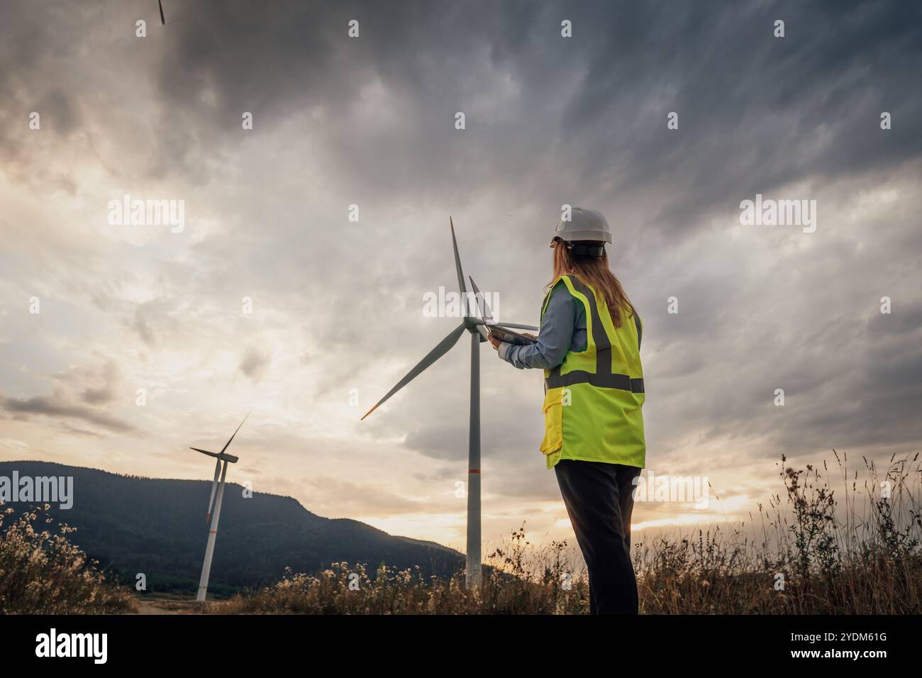 A dedicated female technician is carefully inspecting a wind turbine ...