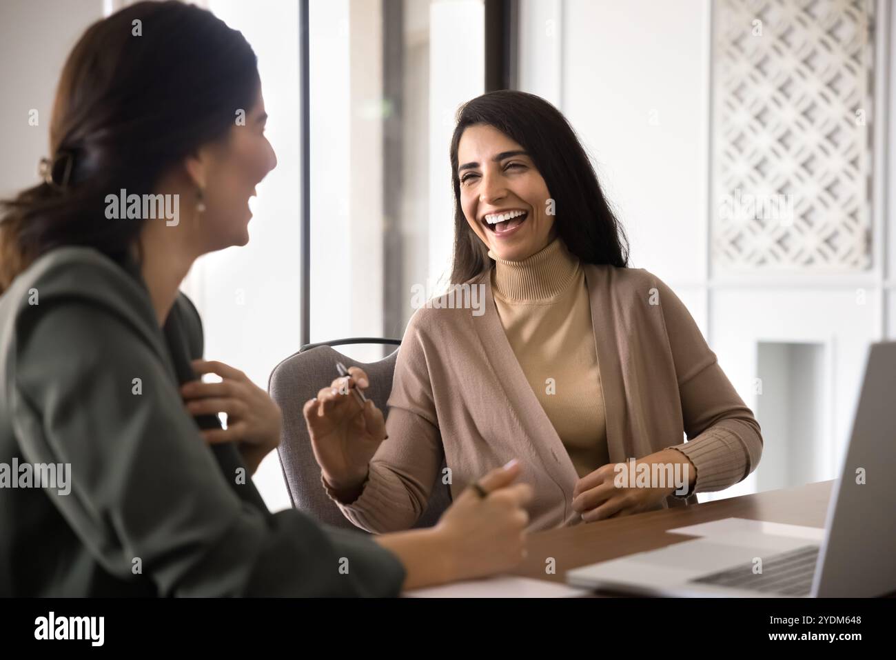 Two happy Hispanic female office friends laughing at workplace Stock ...