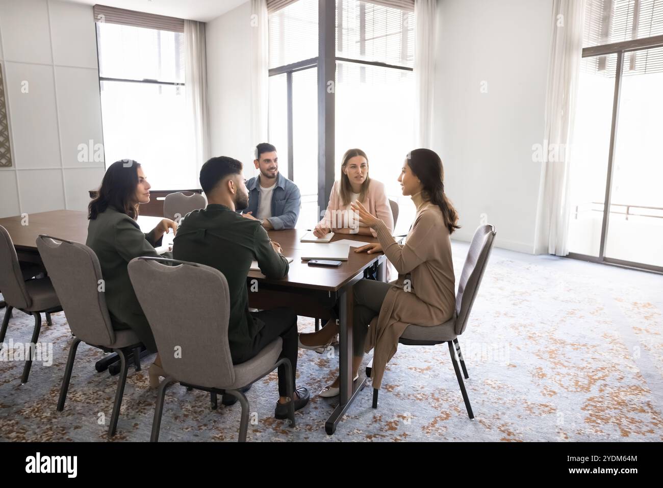 Confident young Latin female business leader speaking at team meeting ...