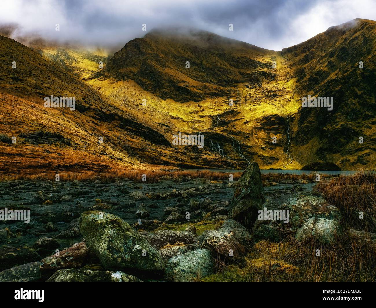 A small, still lake is nestled between two mountain slopes, covered in ...