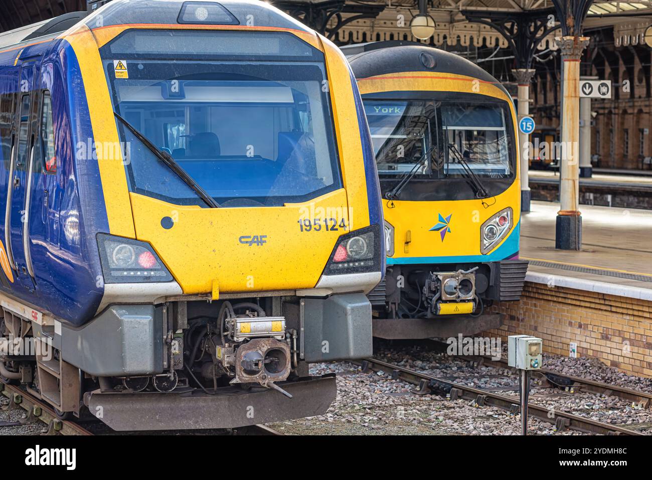 Two trains are stationary beside each other near a historic 19th ...