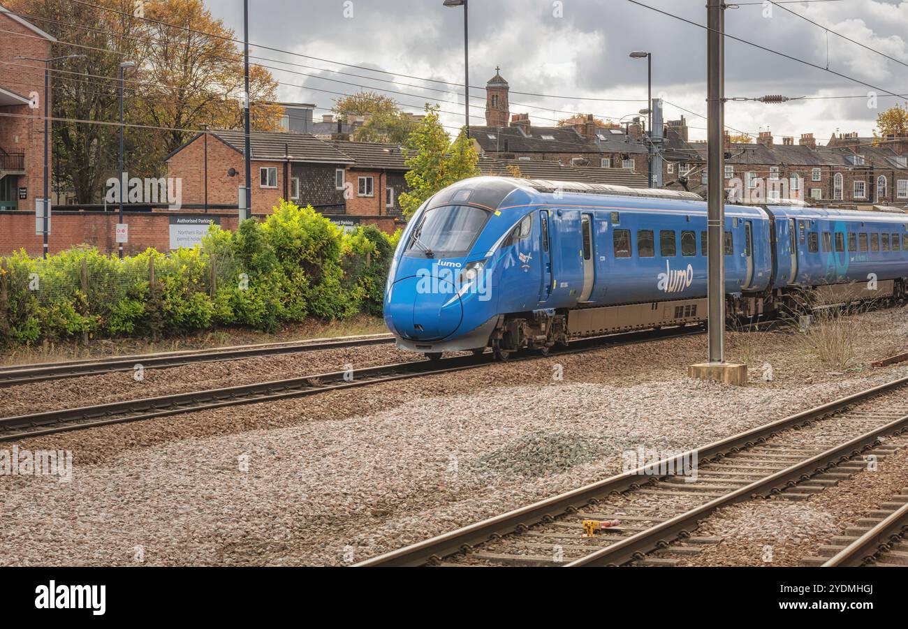 A modern train approaches a railway station with houses and a church ...