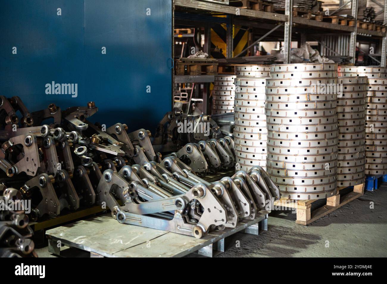 A factory storage area filled with stacks of industrial metal parts and ...