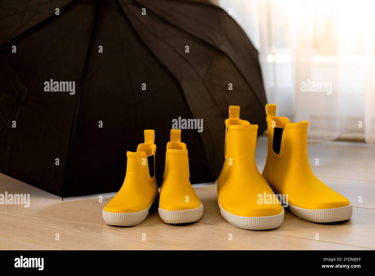 Bright yellow rubber boots for children and adults placed under a black ...