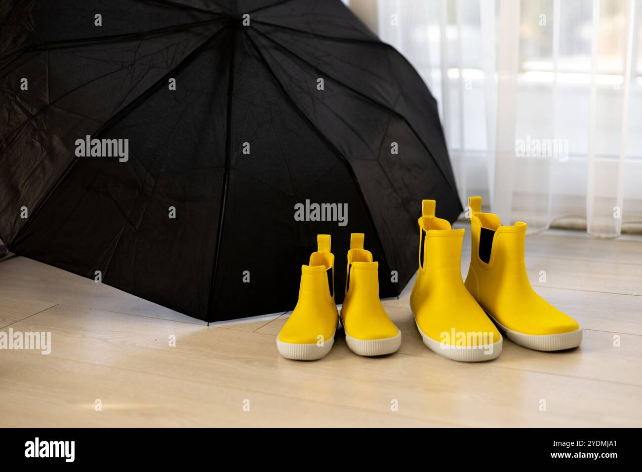 Bright yellow rubber boots for children and adults placed under a black ...