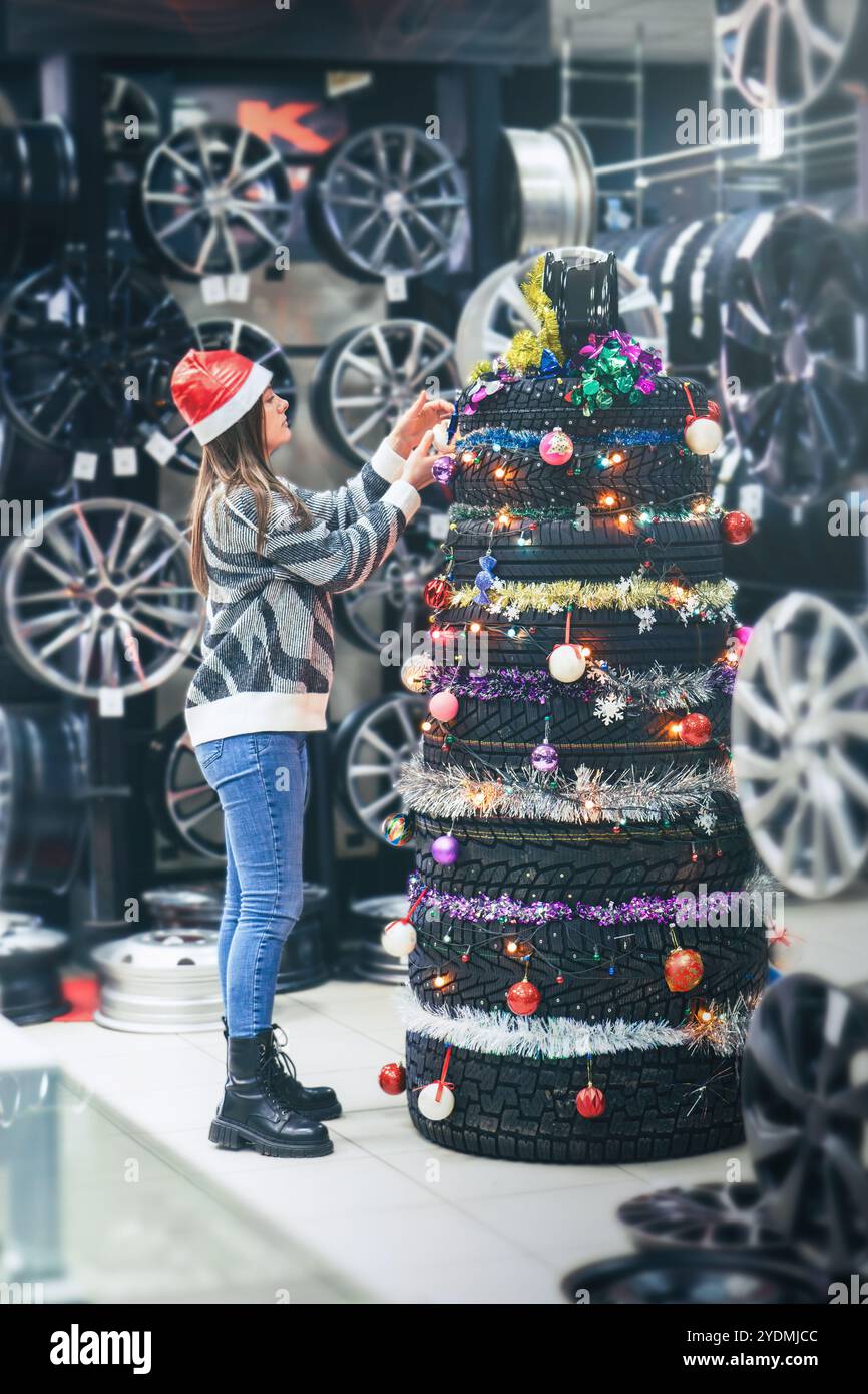 A girl in a Santa hat is creatively decorating a Christmas tree made of ...