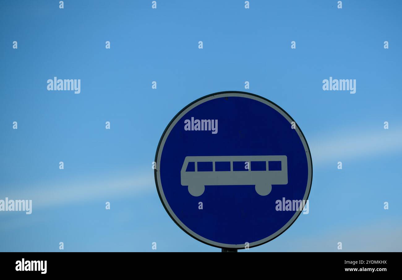 A sign featuring a bus symbol stands prominently against a bright blue ...